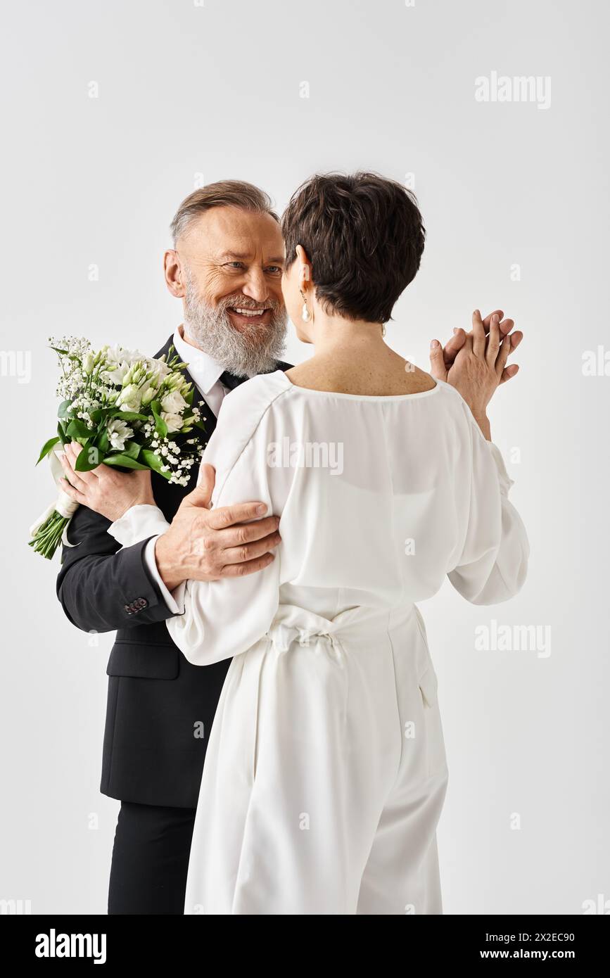 A middle aged man in a tuxedo wrapped in a warm embrace with a woman in ...
