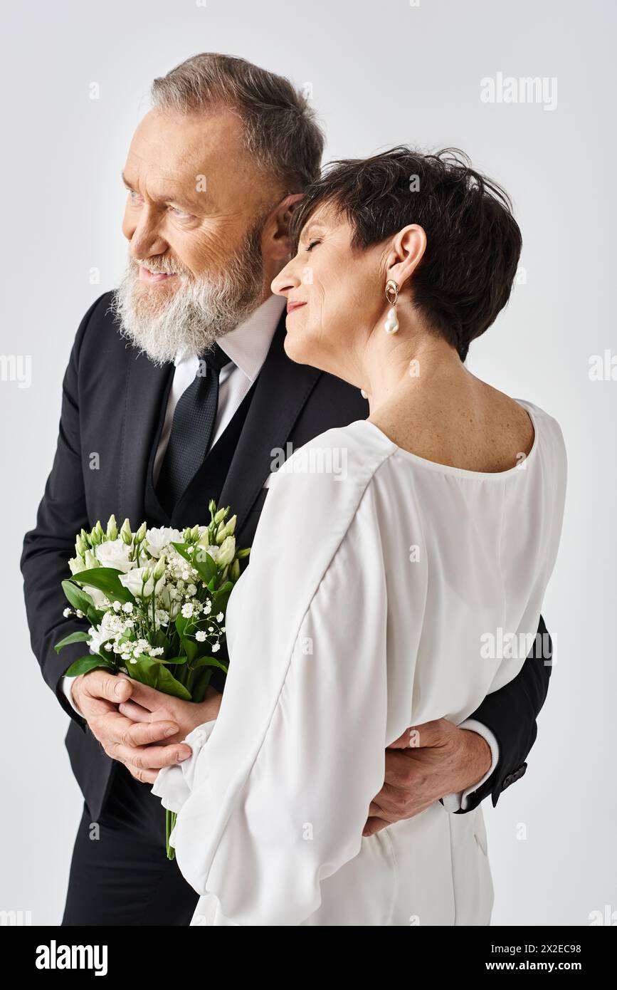 A middle aged bride and groom in wedding attire embrace joyfully in a ...