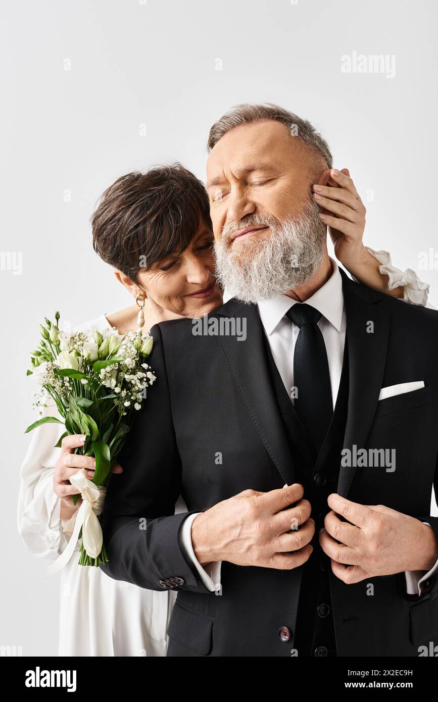 Middle-aged bride and groom in elegant wedding attire embrace each ...