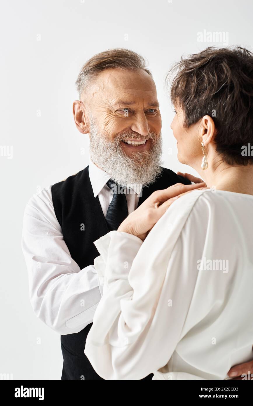 A middle-aged bride and groom in wedding attire standing closely ...