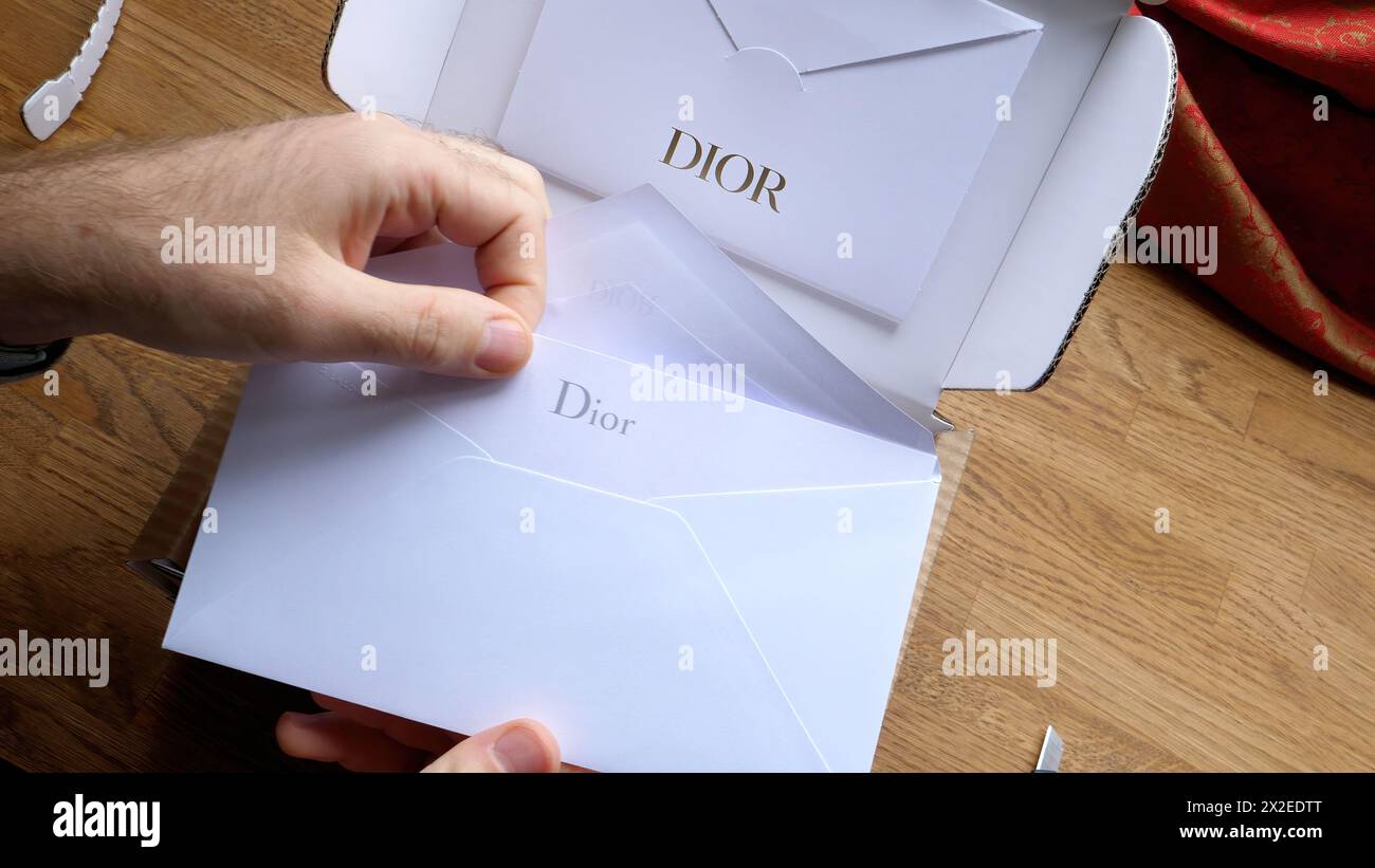 Paris, France - Sep 14, 2023: Male hand opens a Christian Dior envelope ...