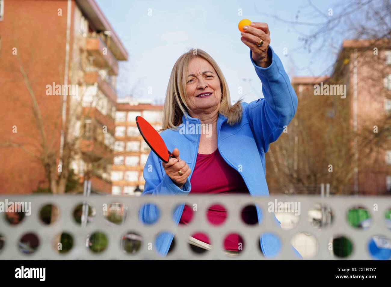 Mature woman holding table tennis ball and rackets in the garden ...