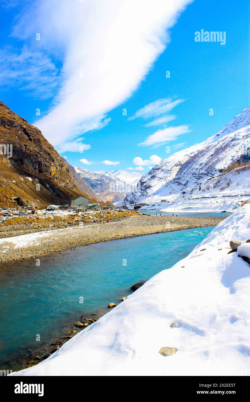 The view of Chandra lake alongside snow capped mountains Stock Photo ...