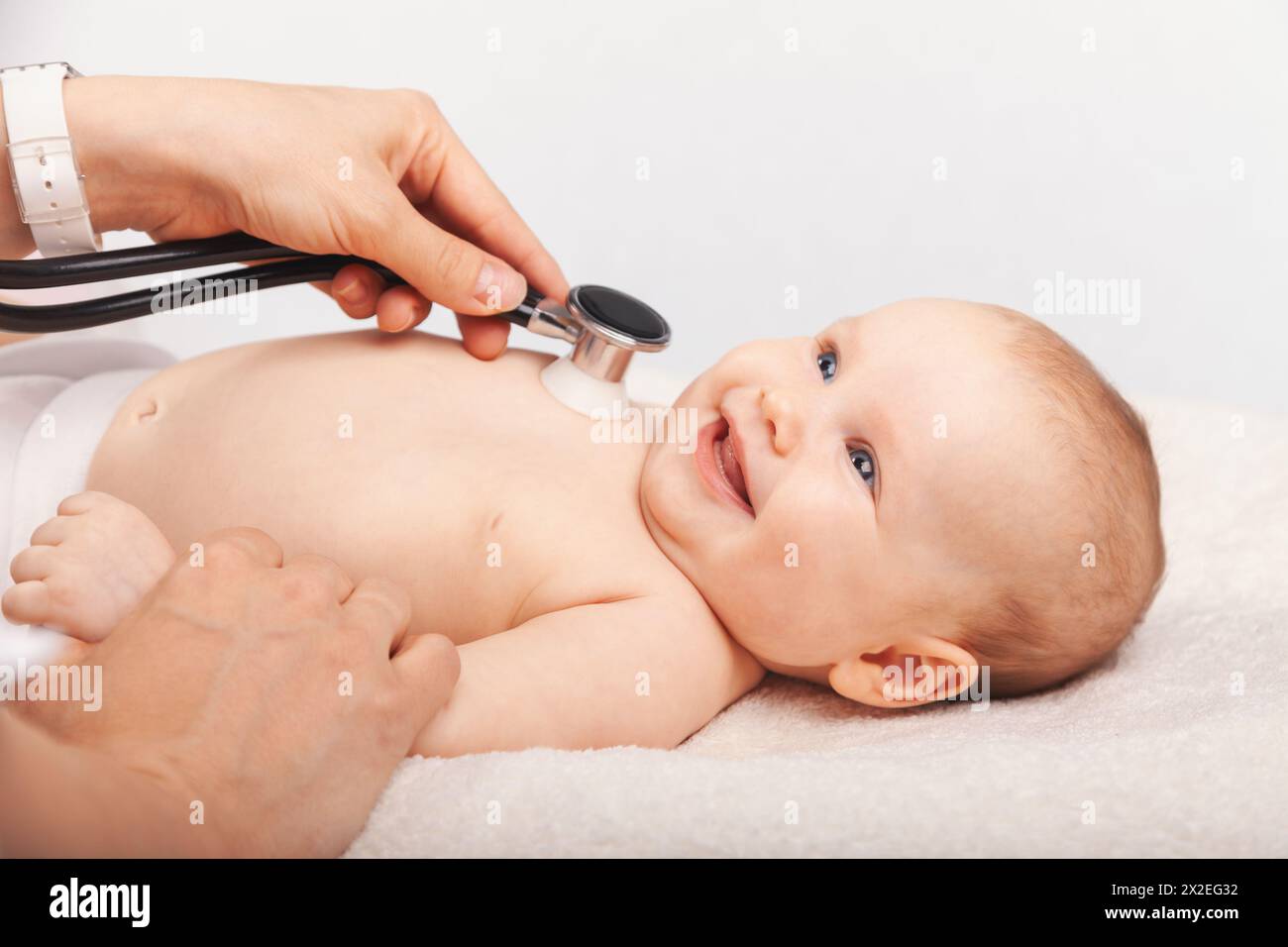 Three month baby girl smiling during medical exam. Doctor using a ...