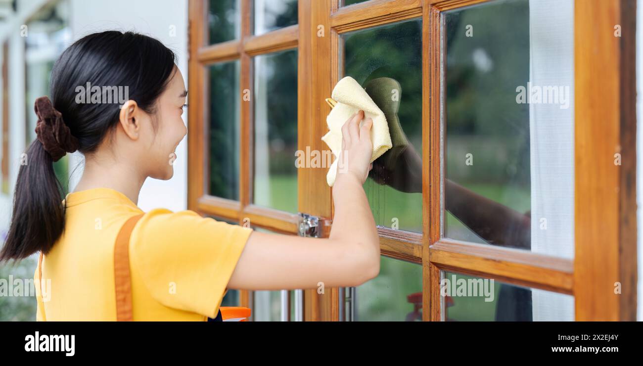 Woman doing household chores and wiping windows in the house on ...