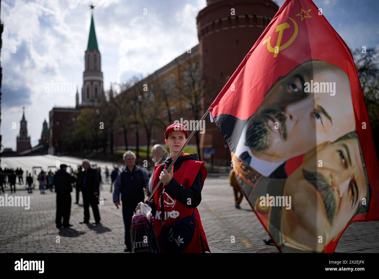 A young man holds a red flag with images of Soviet founder Vladimir ...