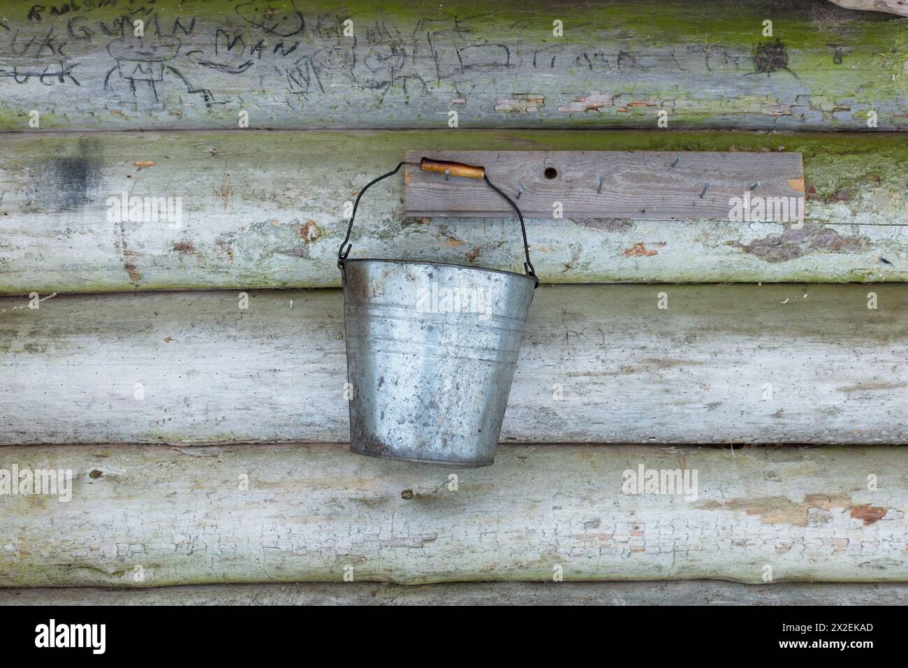 Old retro bucket hanging on wooden shelter wall Stock Photo - Alamy