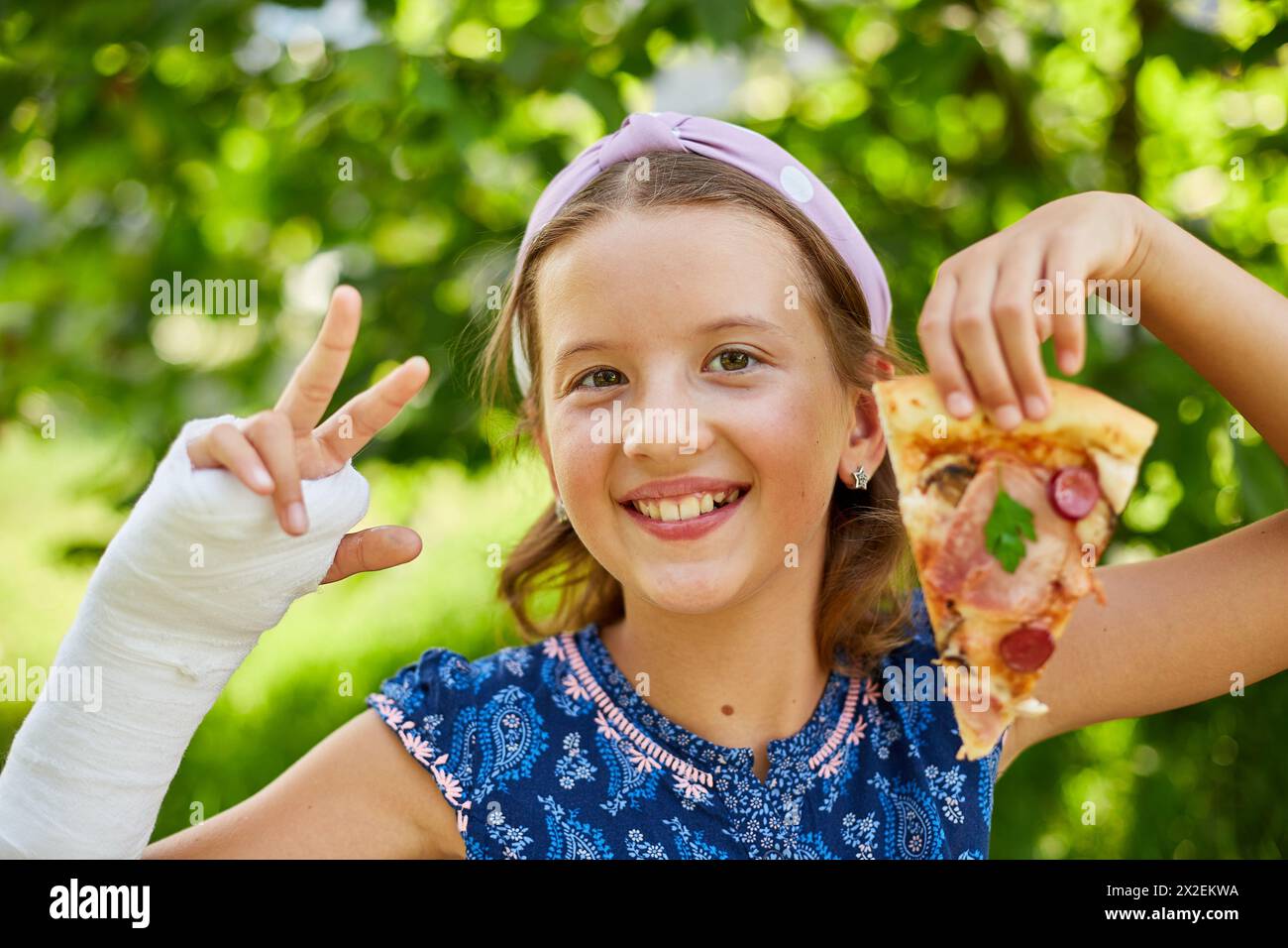 A cheerful girl with a white cast on her arm is playfully covering one ...