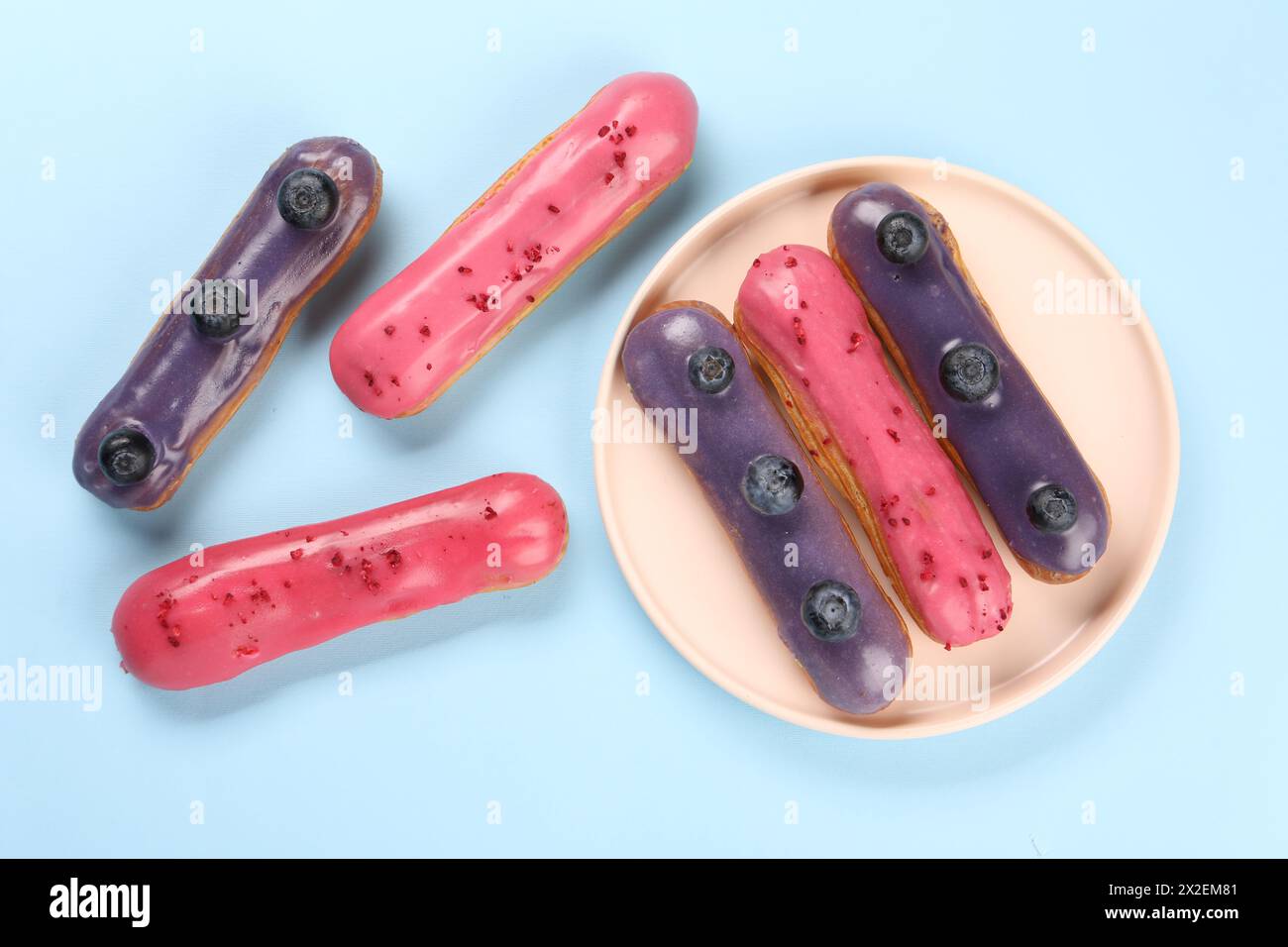 Delicious eclairs covered with glaze on light blue background, top view ...