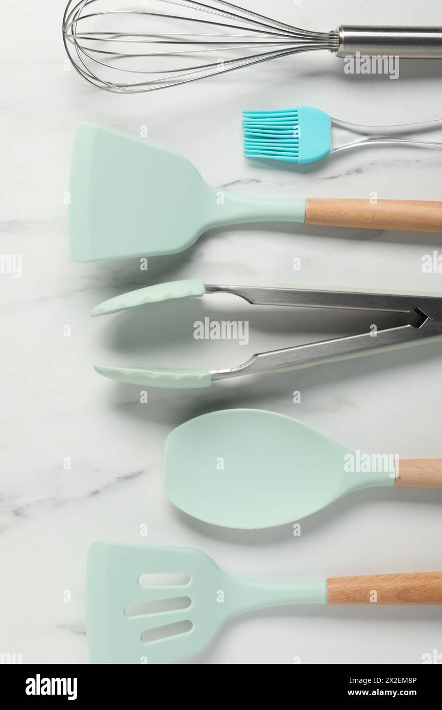 Different spatulas and other kitchen utensils on light marble table ...
