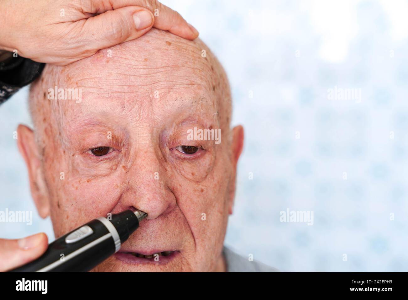 A bald old man is getting his nose shaved with a tool Stock Photo - Alamy