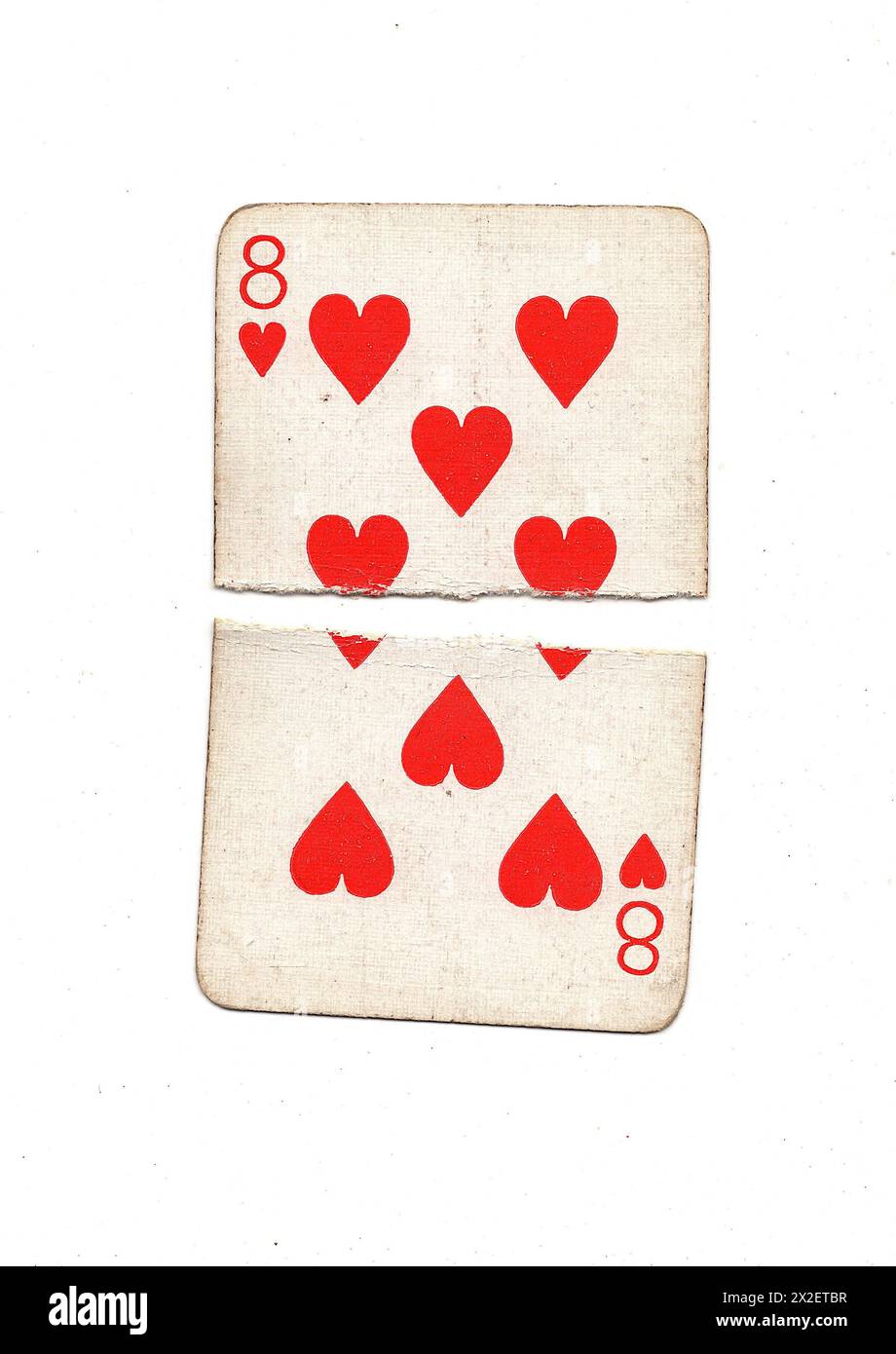 A vintage, well used eight of hearts playing card torn in half on a ...