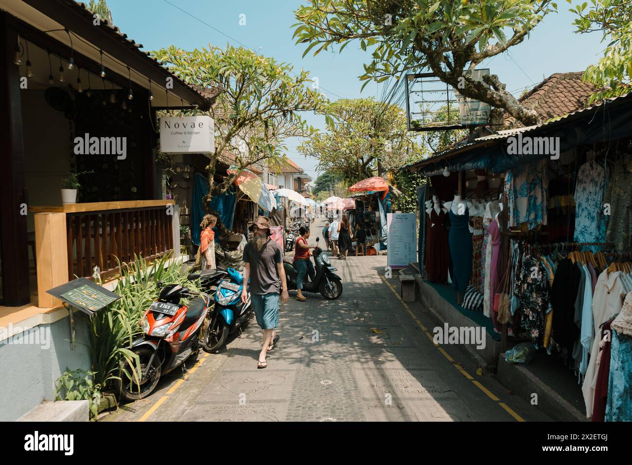 Tourist walking and local seller in narrow street in Ubud traditional ...