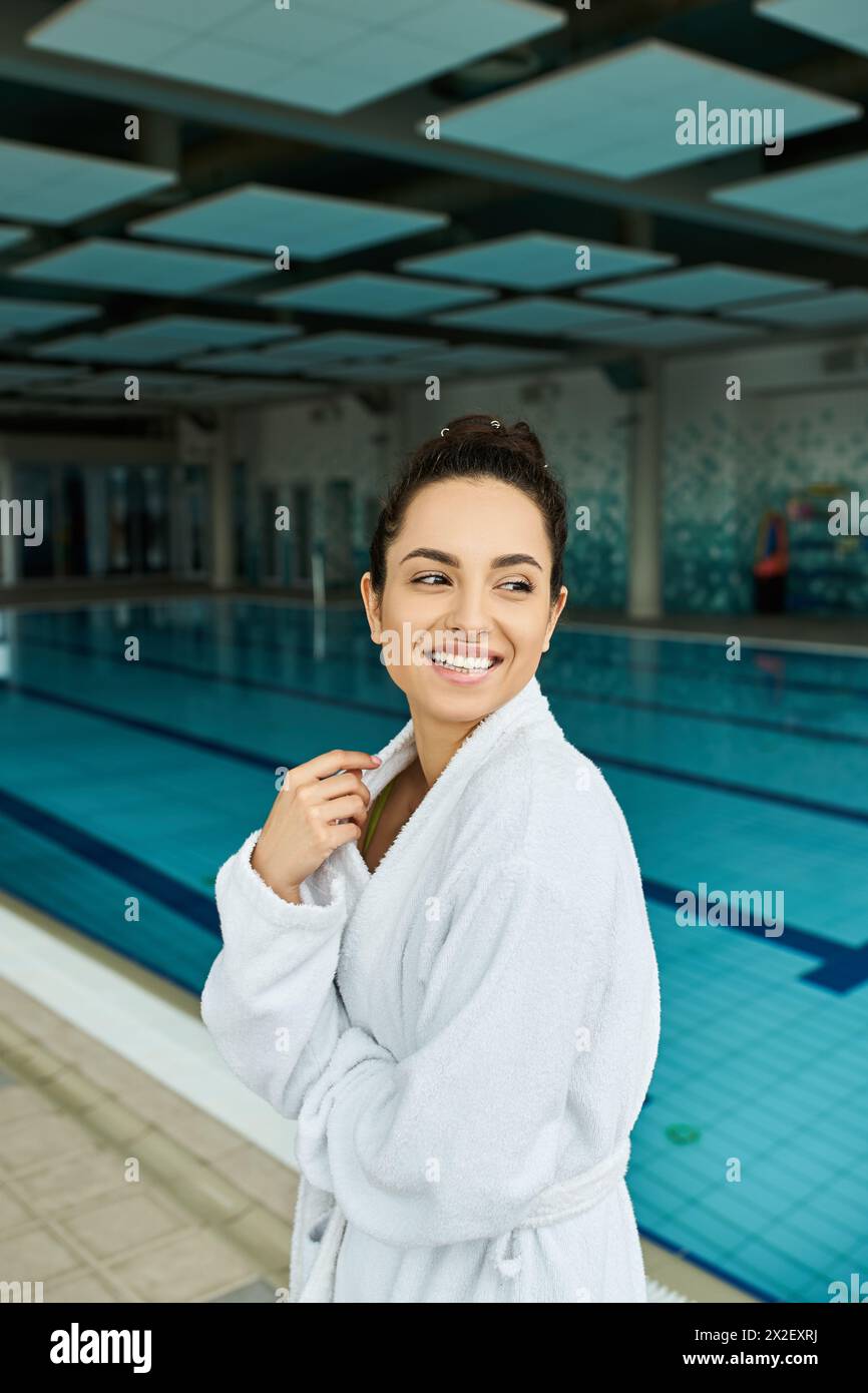 A young and beautiful brunette woman in a bathrobe standing calmly in ...