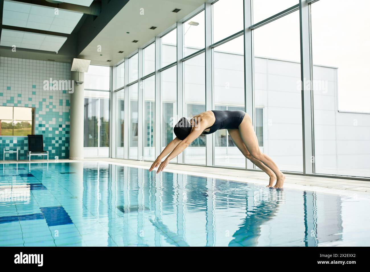 Elegant young woman in black swimsuit gracefully diving into a serene ...