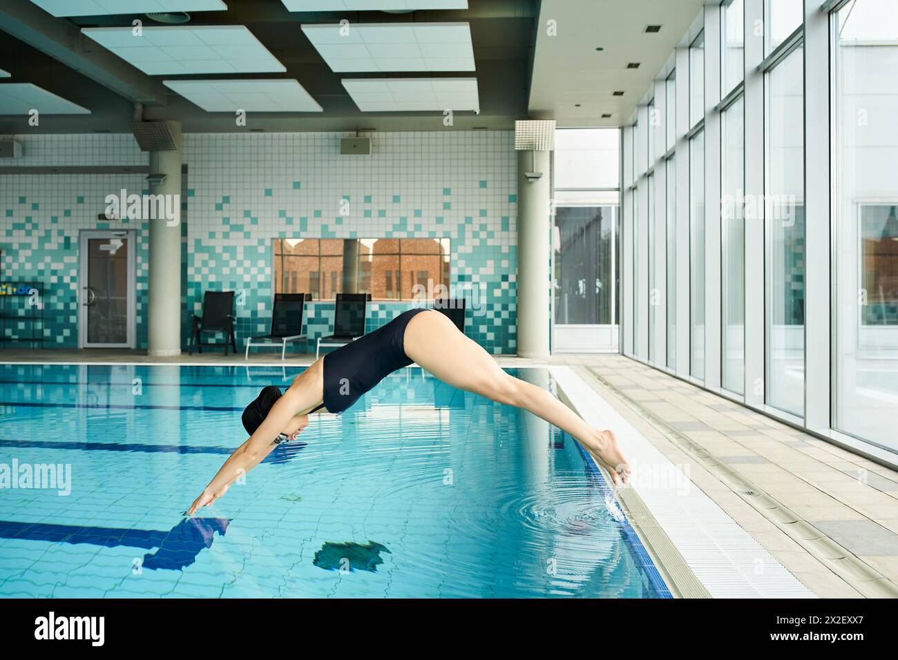 A young woman in a swimsuit and swim cap gracefully dives into a ...