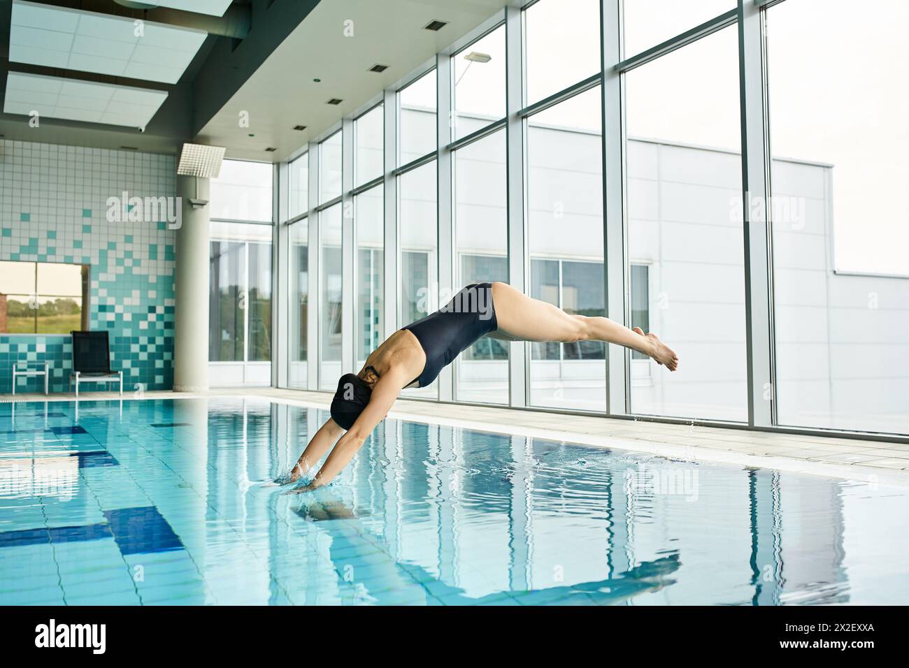 A man in mid-air, diving into a swimming pool with precision and ...
