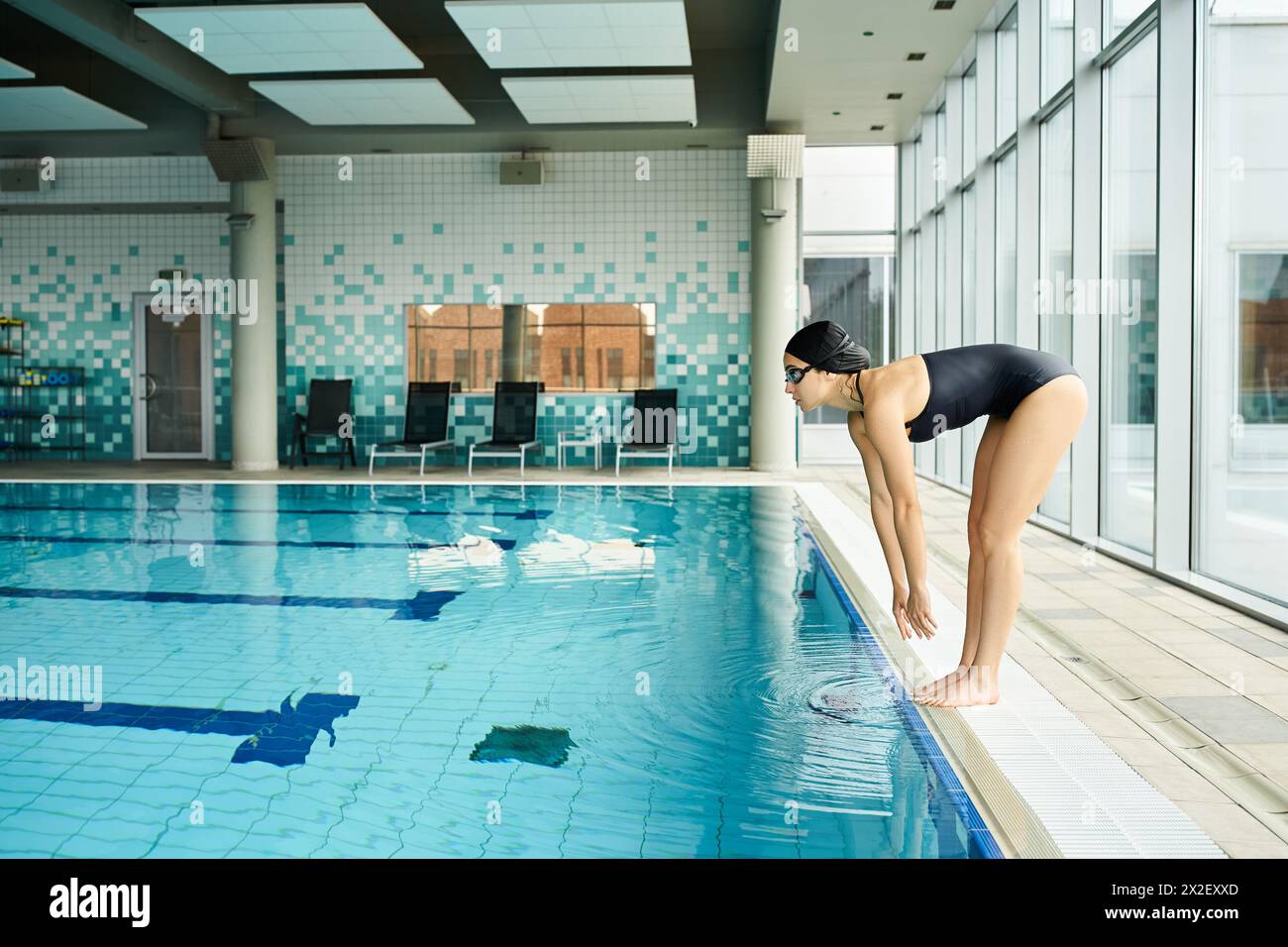 A young woman in a black bathing suit stands on a ledge next to an ...