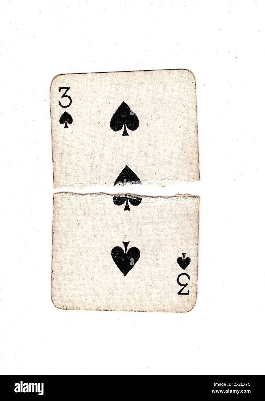A vintage, well used three of spades playing card torn in half on a ...