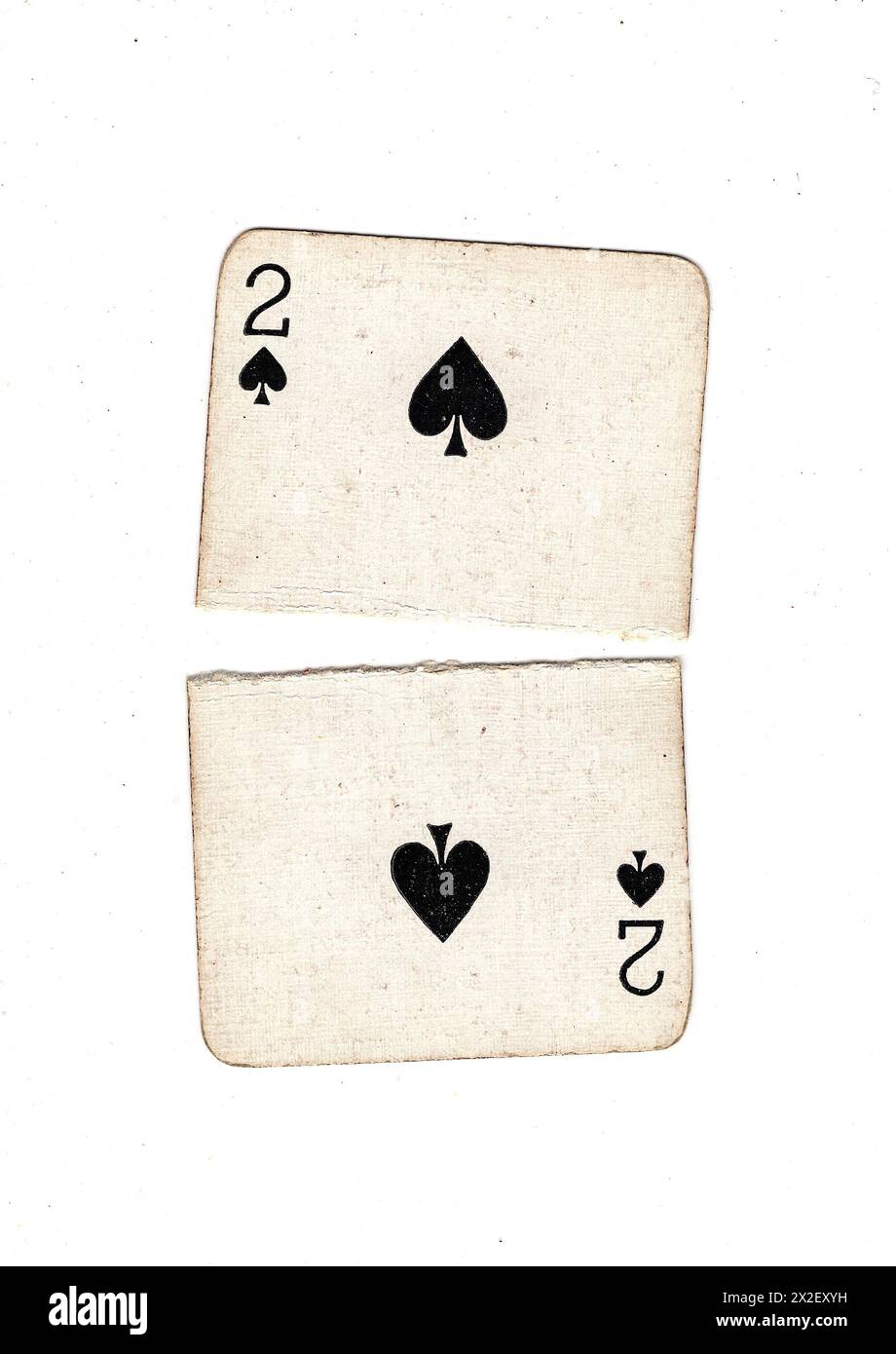 A vintage, well used two of spades playing card torn in half on a white ...