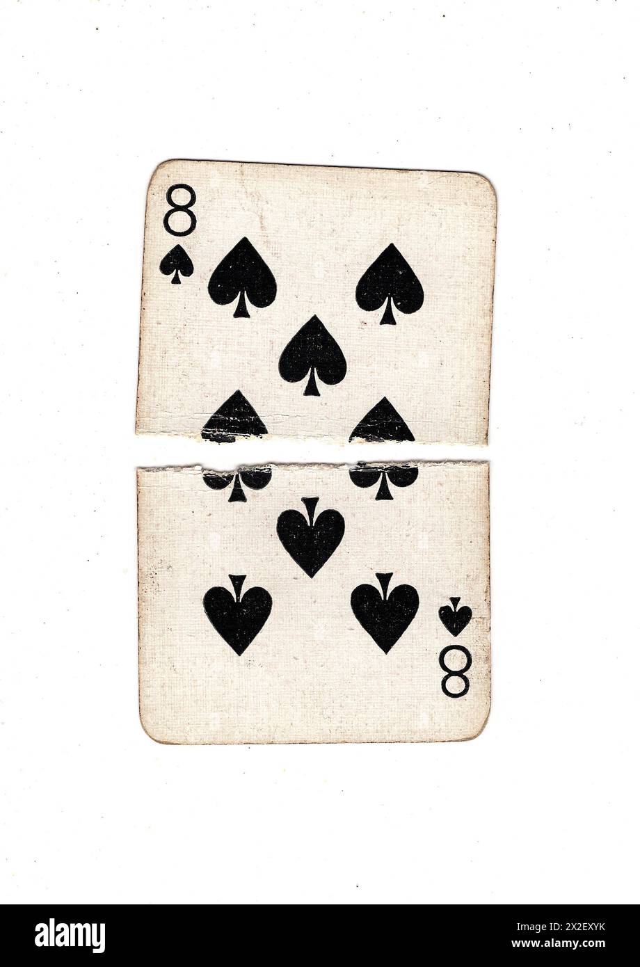 A vintage, well used eight of spades playing card torn in half on a ...