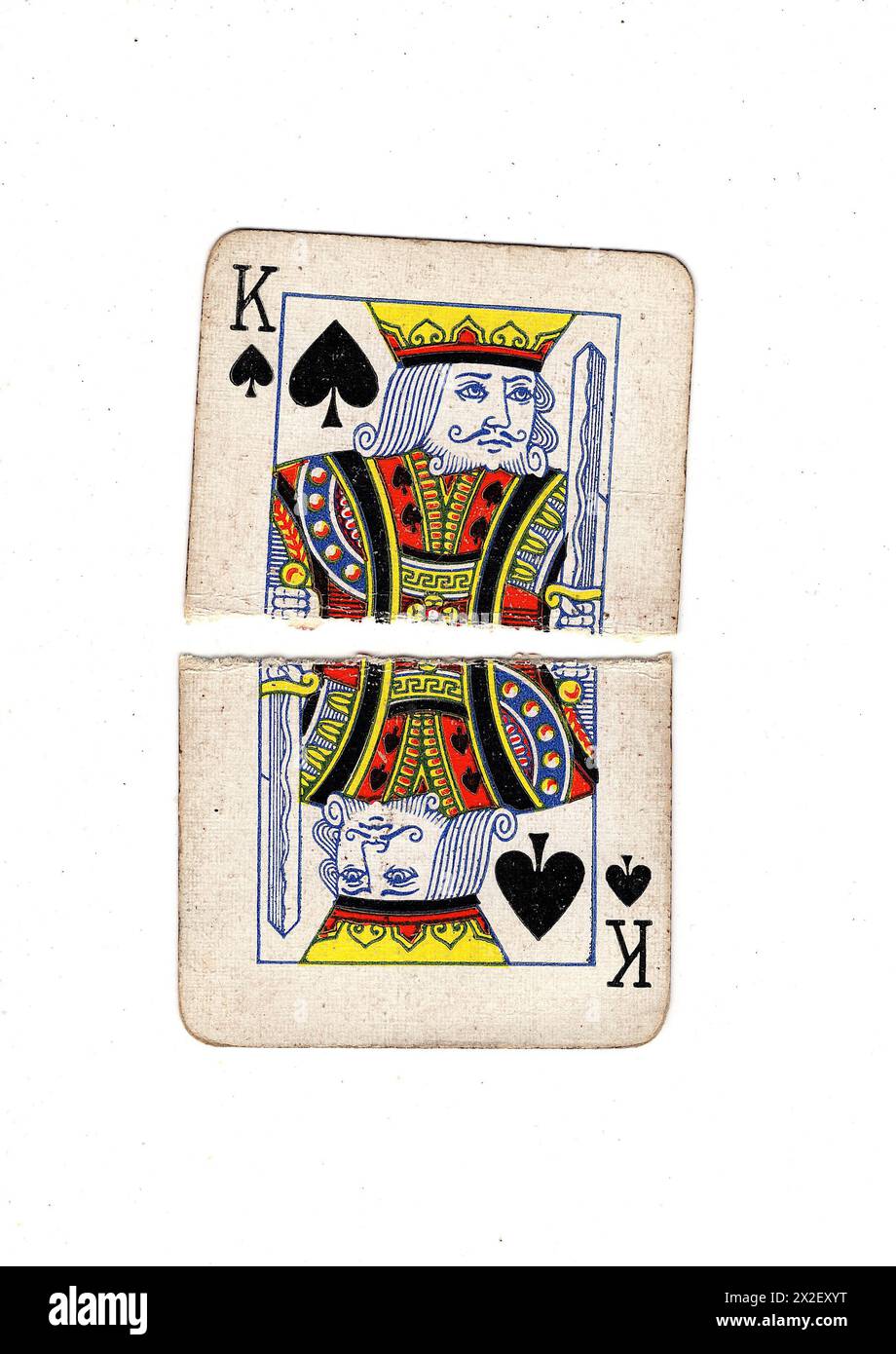 A vintage, well used king of spades playing card torn in half on a ...