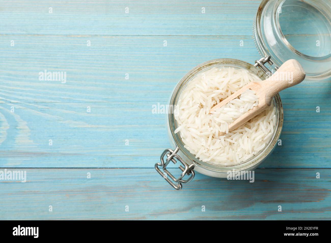 Raw basmati rice in jar and scoop on light blue wooden table, top view ...