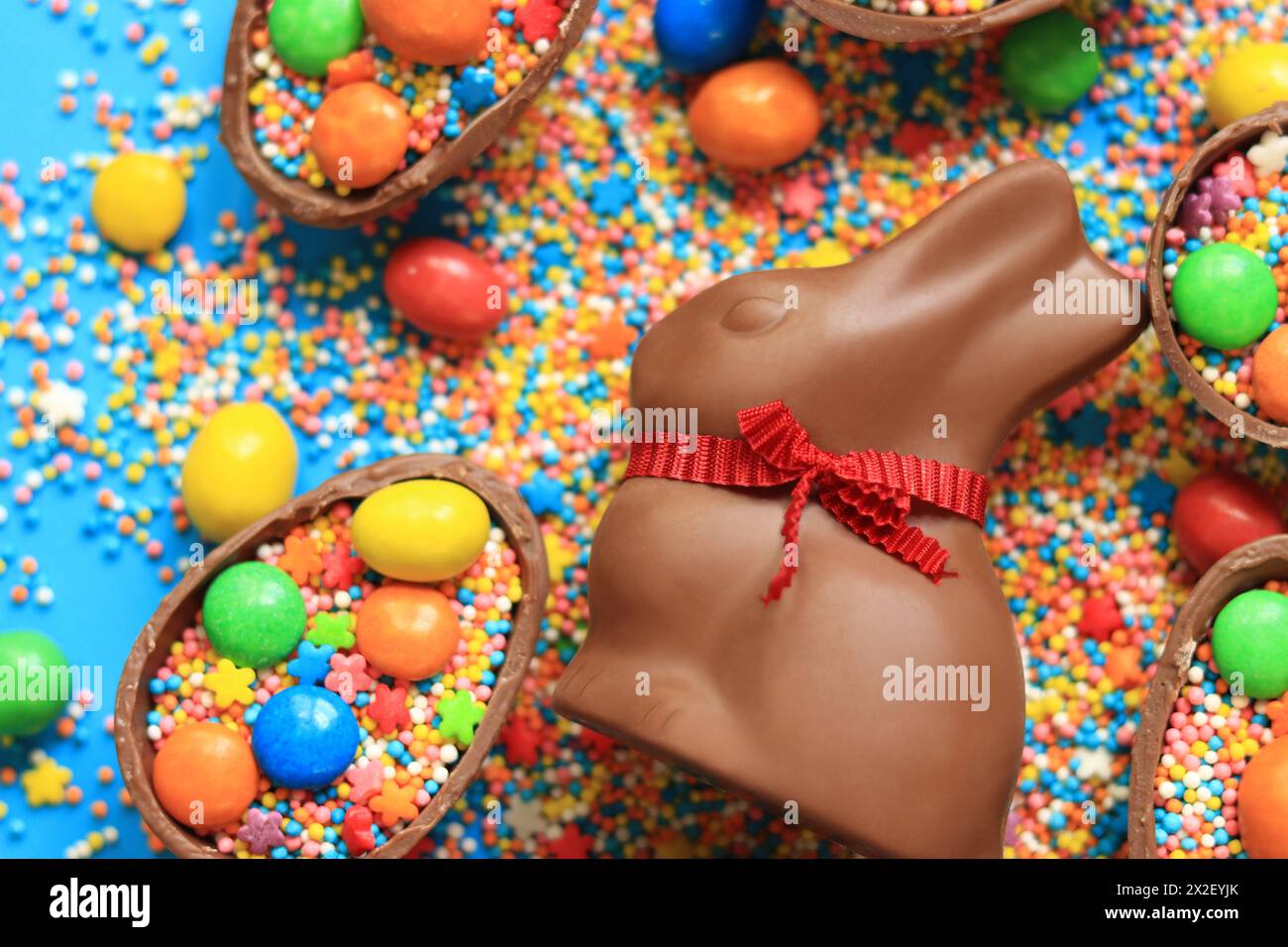 Chocolate bunny and candy, colored sugar sprinkles on a blue background ...