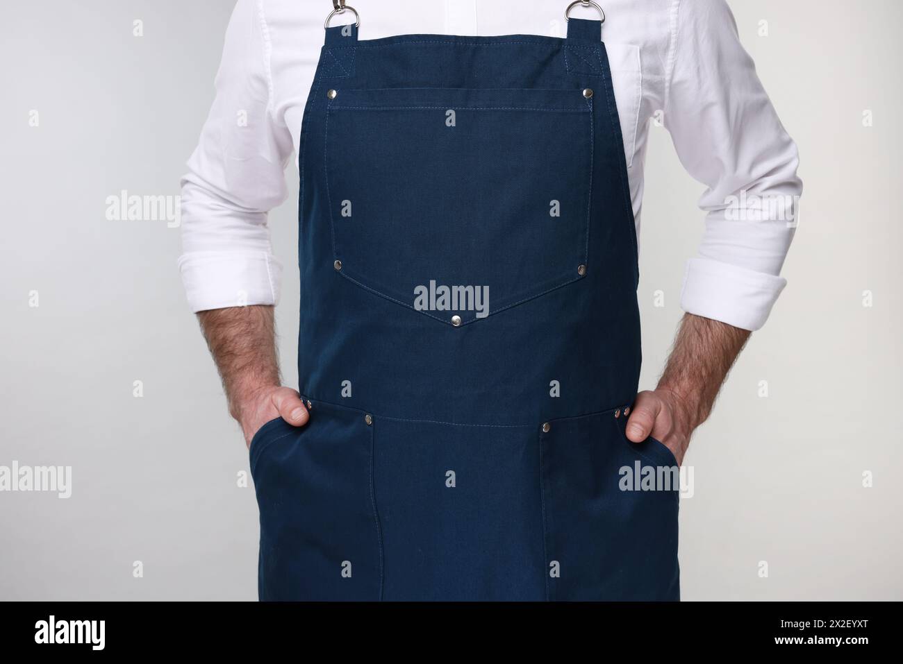 Man wearing kitchen apron on grey background, closeup. Mockup for ...