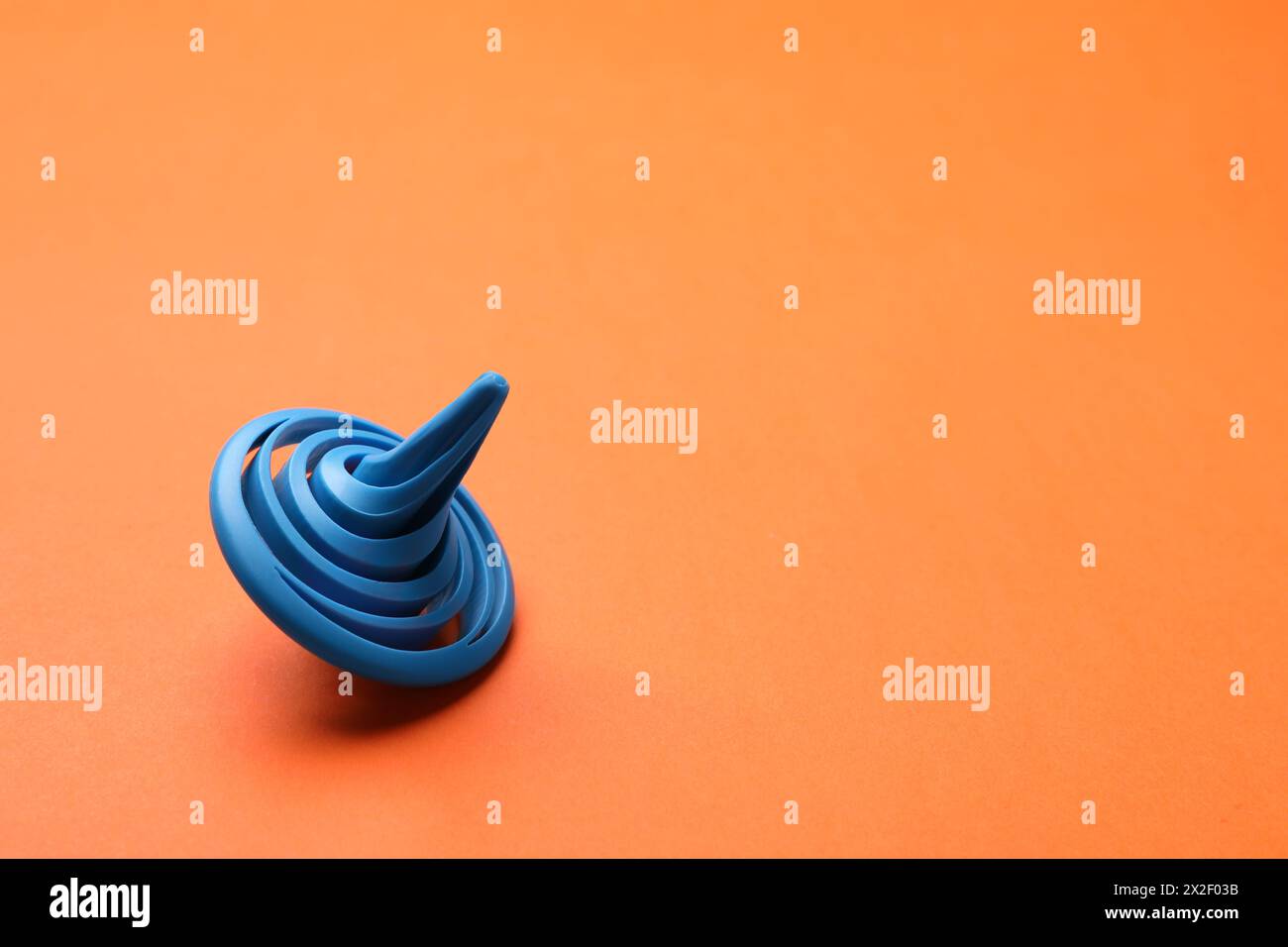 One blue spinning top on orange background Stock Photo - Alamy