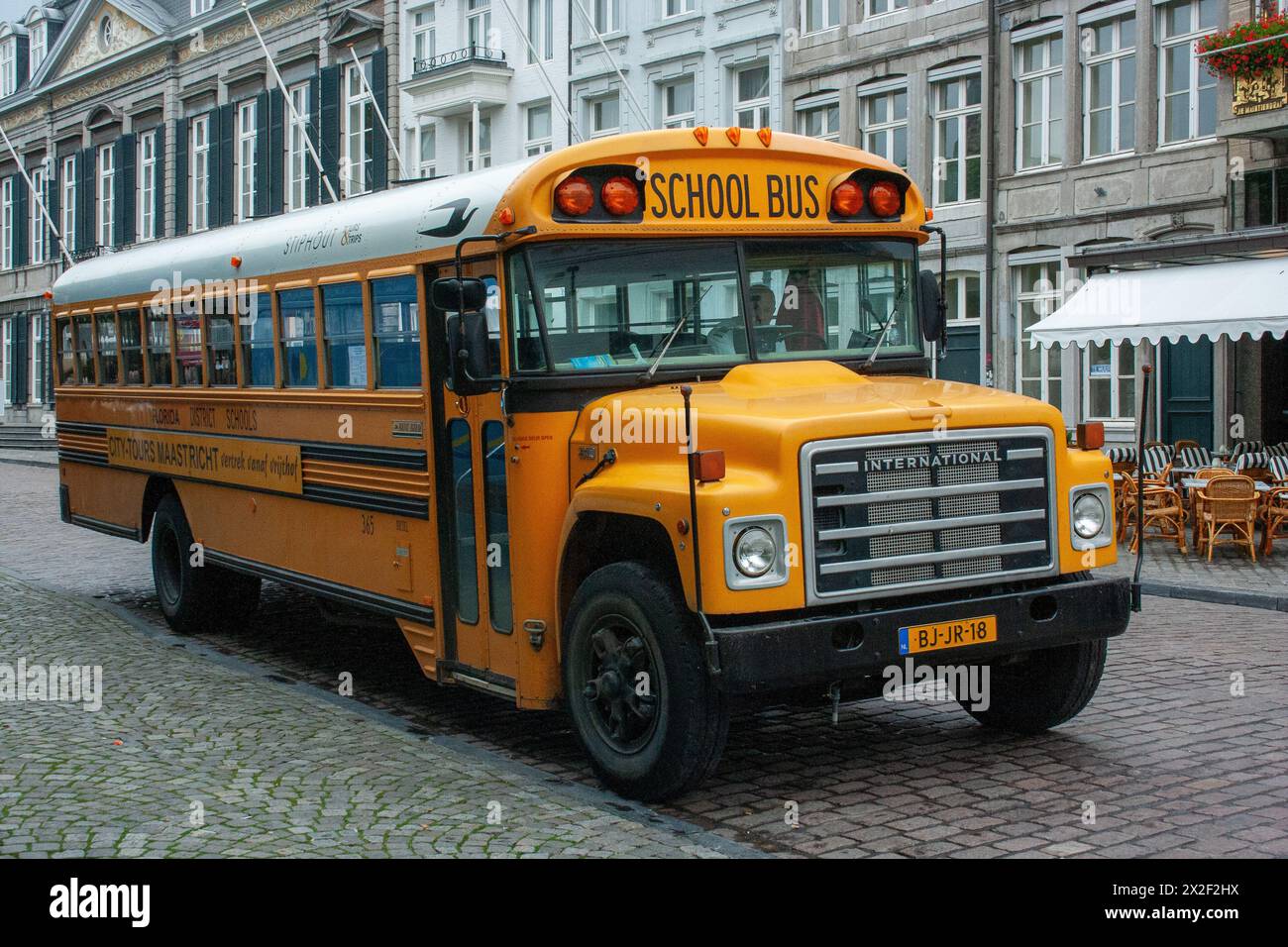 Urban scene, yellow school bus in the city centre of Maastricht ...