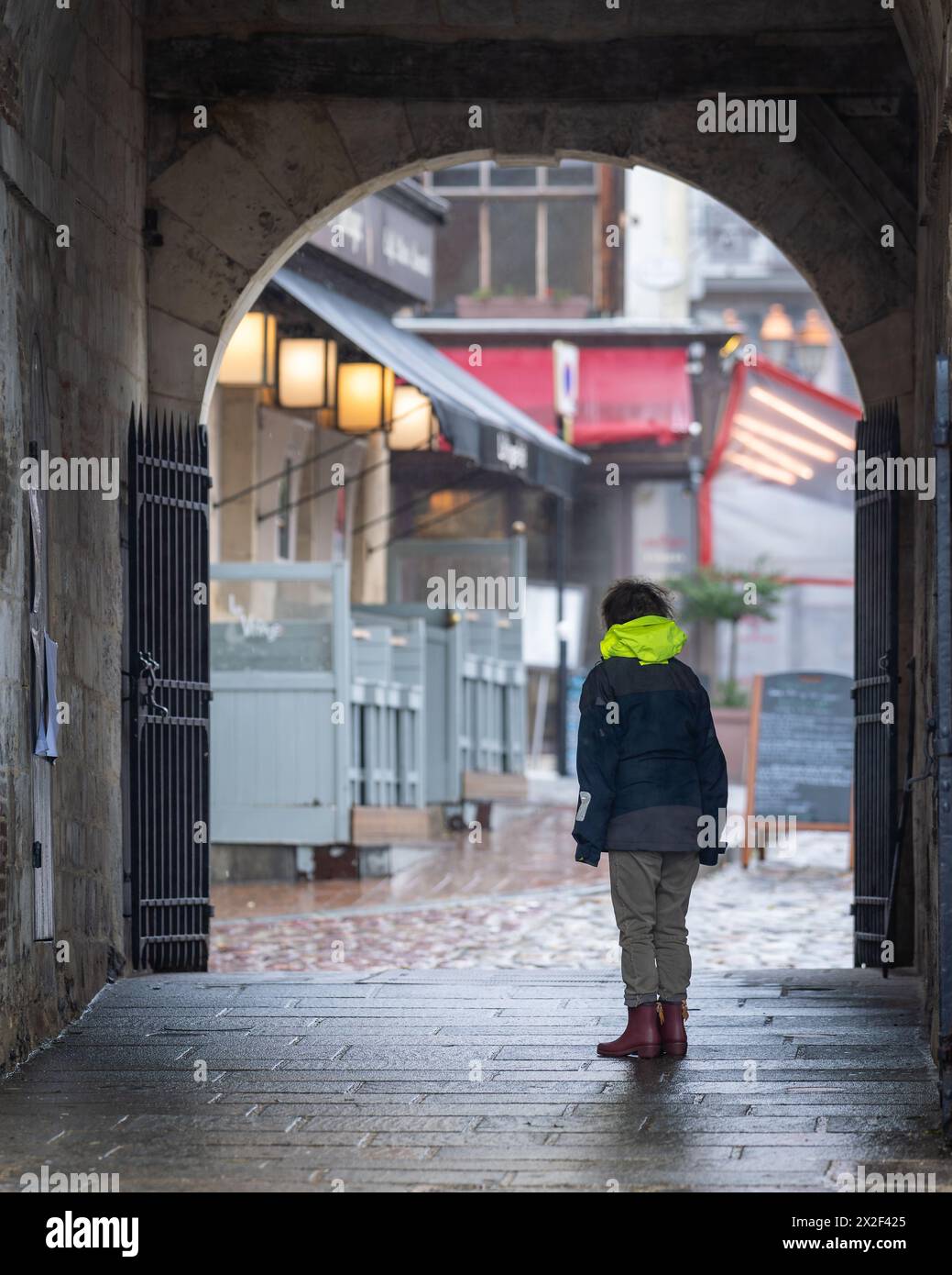 Rainy autumn day. Woman hiding from rain under the arch of the city ...