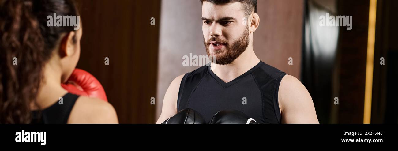 A male trainer in boxing gloves talking to a brunette sportswoman in ...
