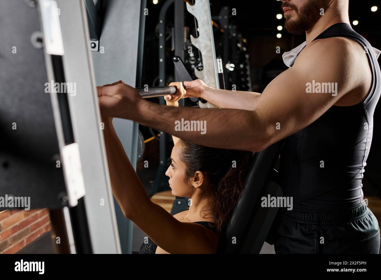 A male personal trainer guides a brunette sportswoman in a gym workout ...