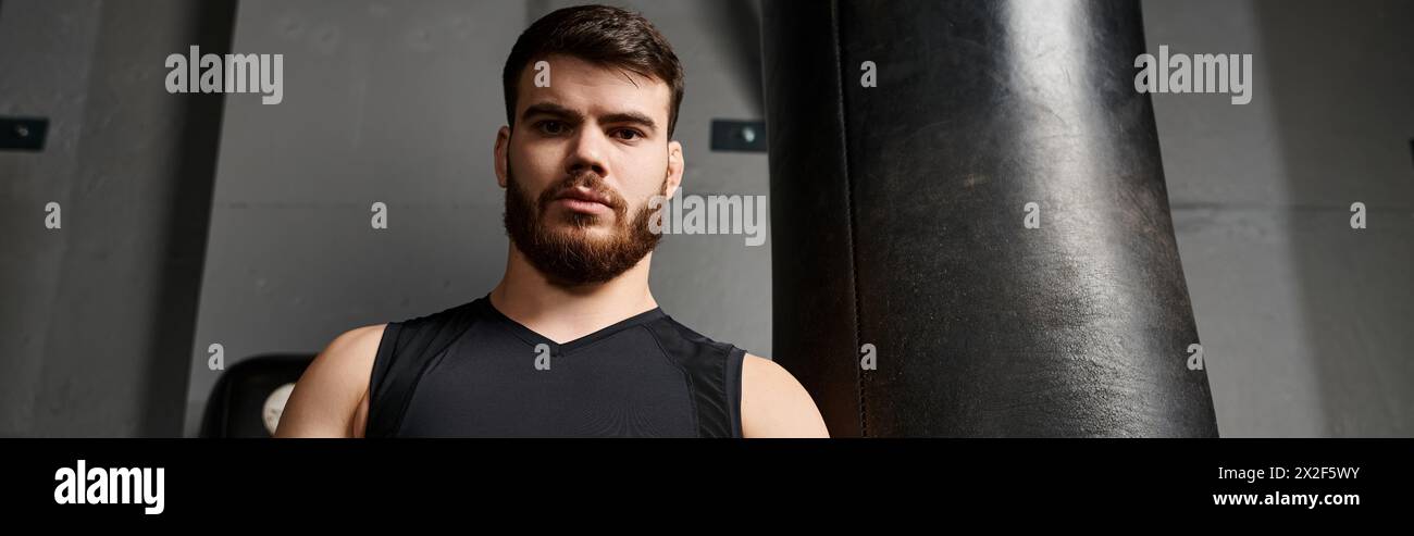 A handsome man with a beard boxing next to a punching bag in a gym ...