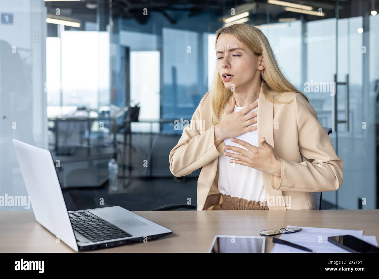A young businesswoman feeling sudden chest pain, gasping for breath at ...