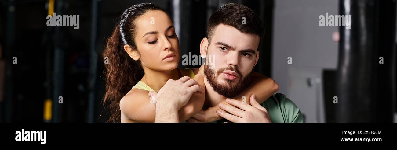A male trainer holds a woman in his arms, demonstrating self-defense ...