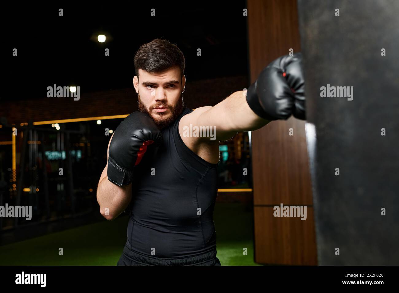 A bearded man in a black shirt trains in a gym, throwing punches at a ...
