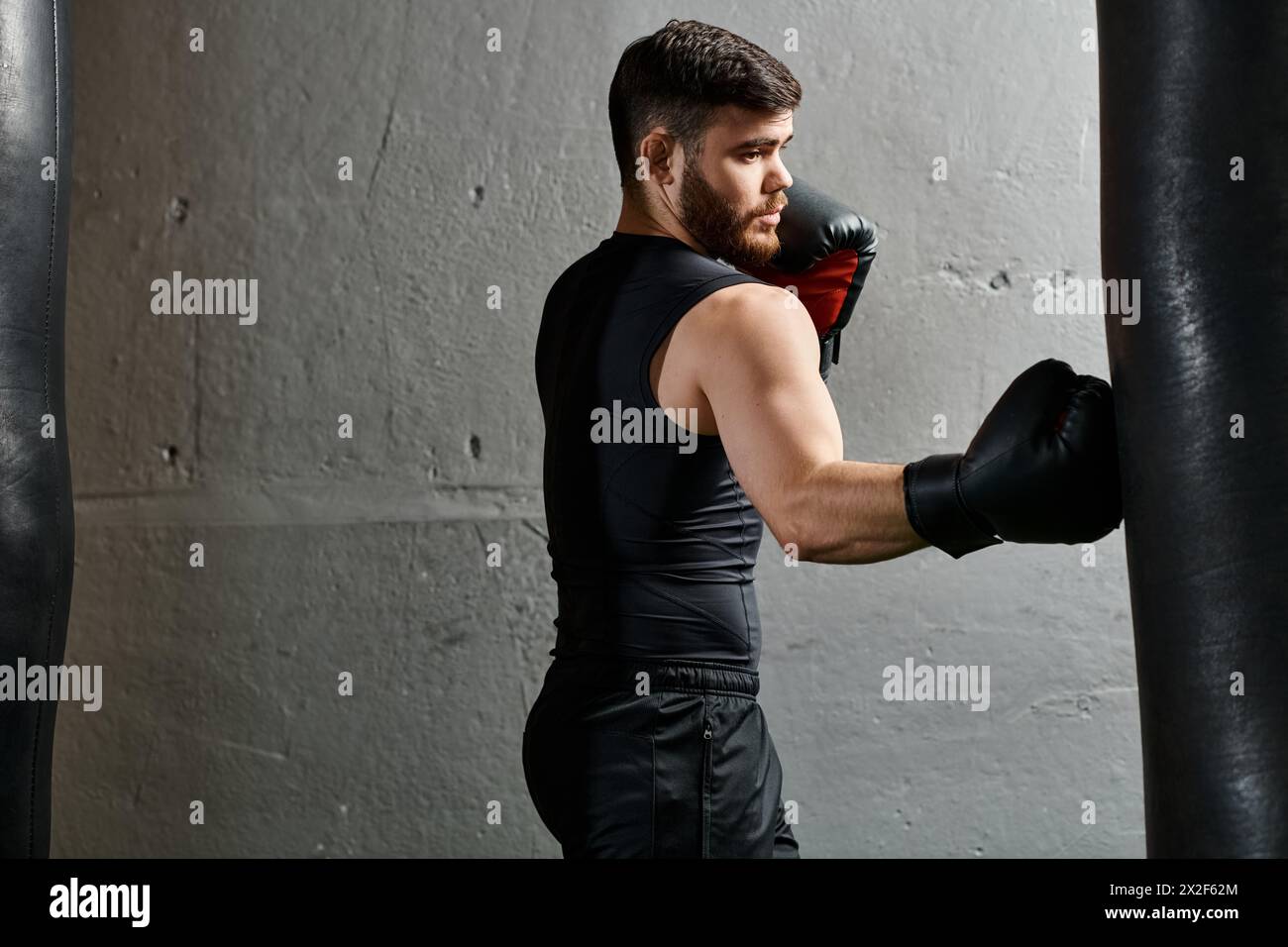 A handsome man with a beard wearing a black shirt and red boxing gloves ...