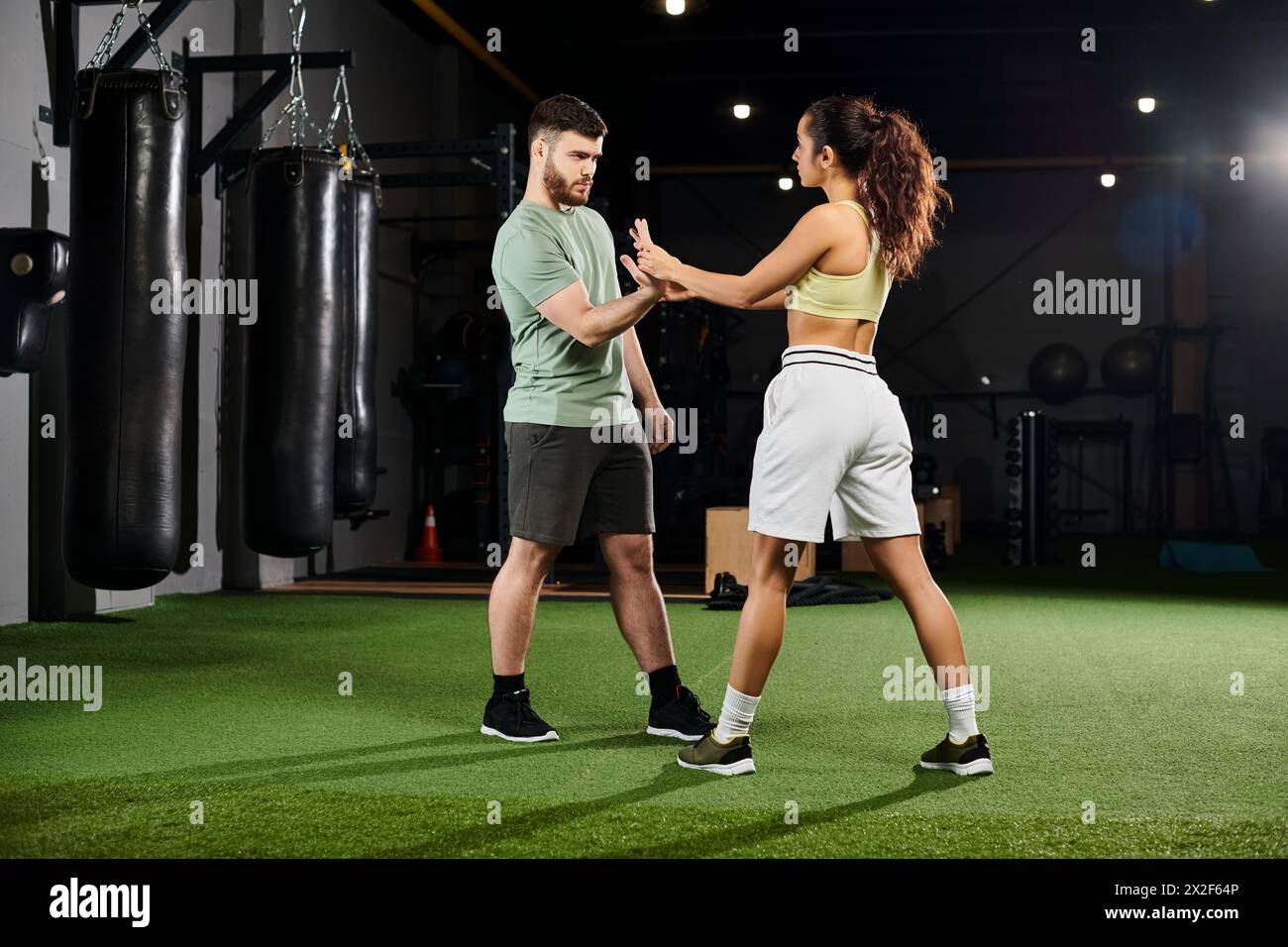 A male trainer demonstrates self-defense techniques to a woman in a gym ...