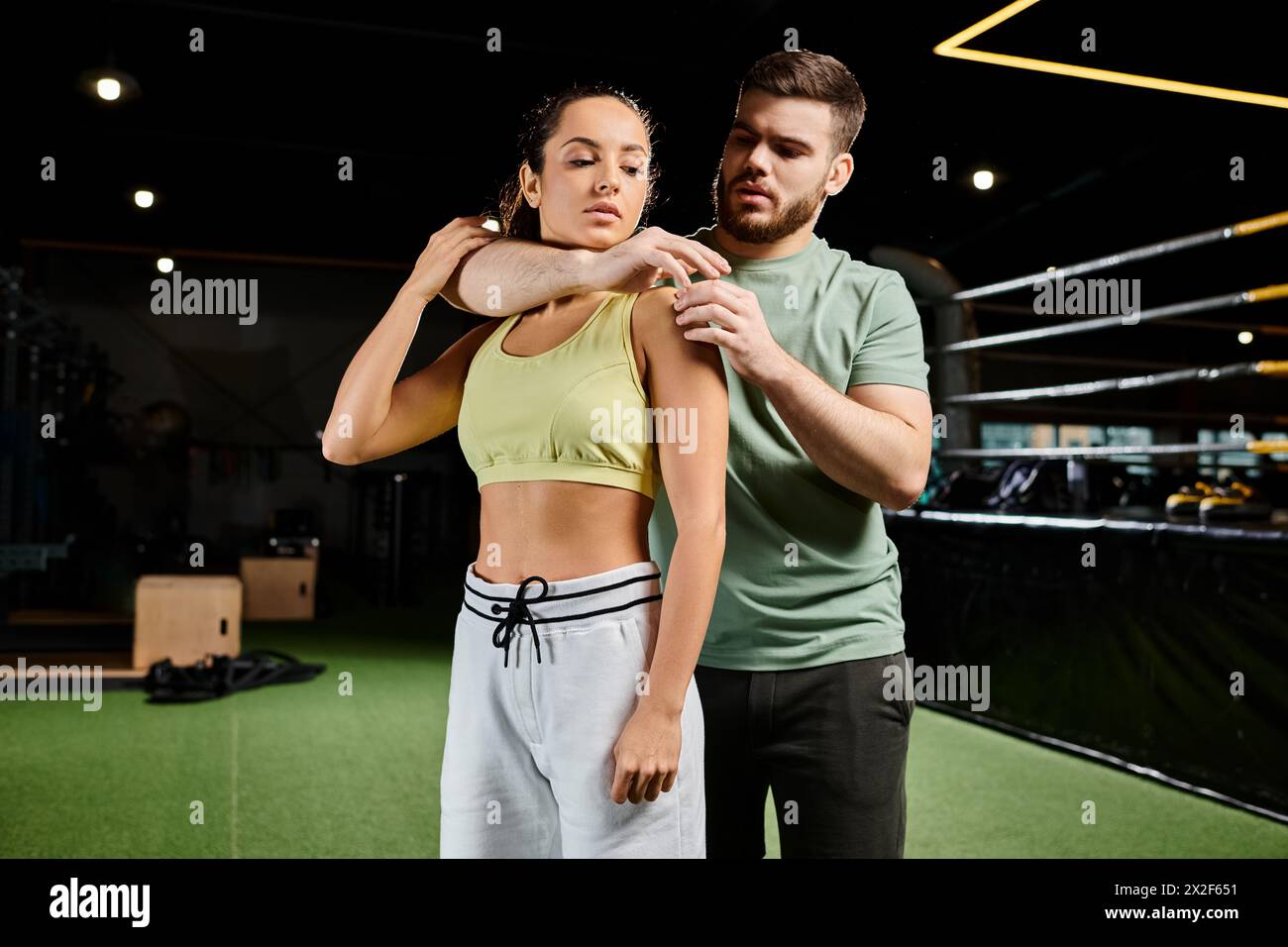 A male trainer is demonstrating self-defense techniques to a woman in a ...