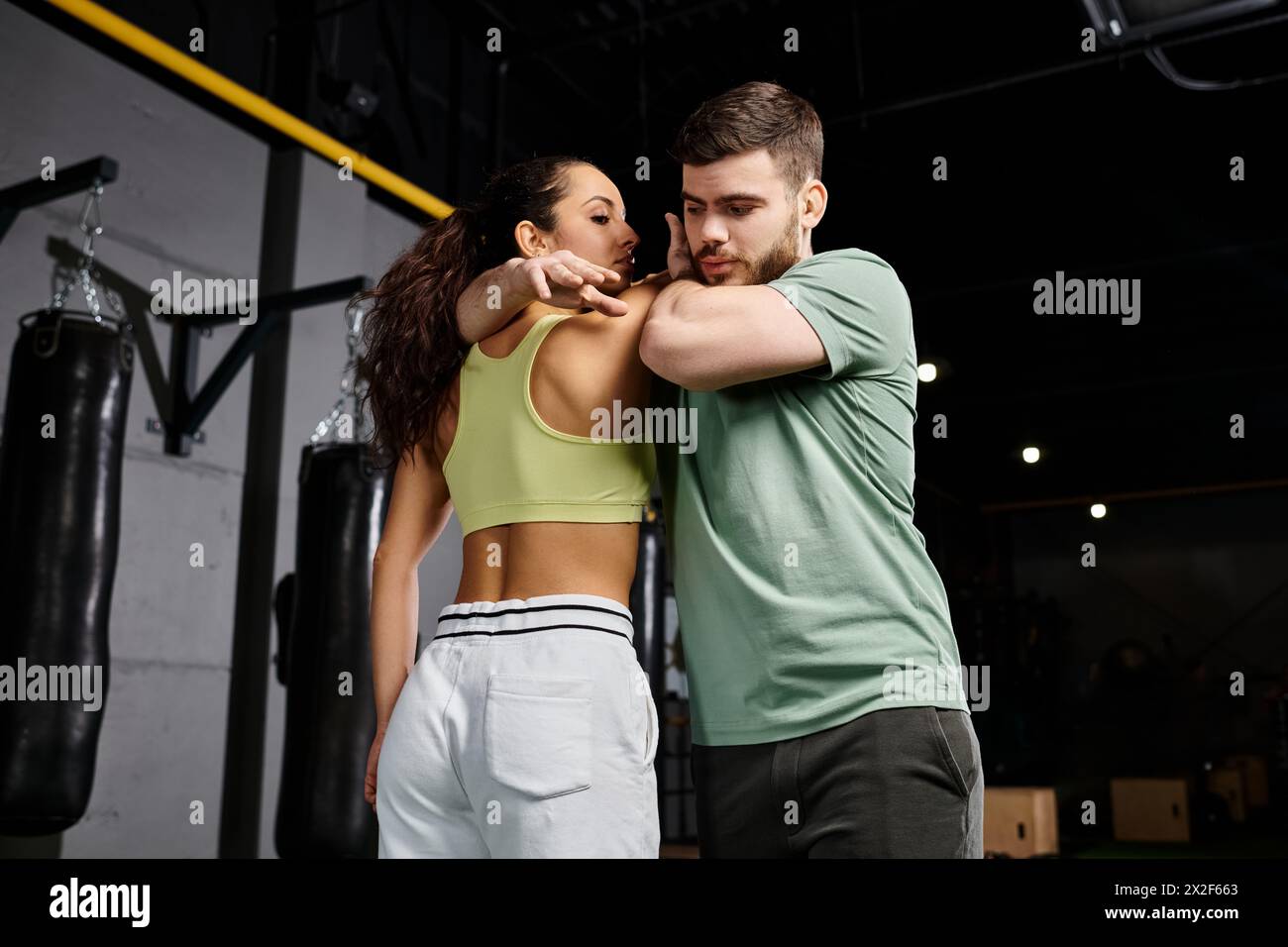 Male trainer demonstrates self-defense techniques to a female client in ...