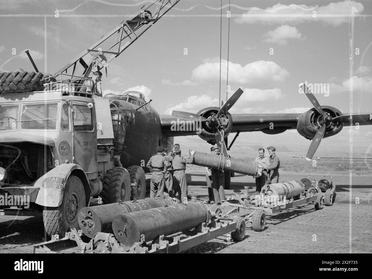 Ground crew of No. 178 Squadron RAF work with No. 61 Repair and Salvage Unit to load sea mines ...