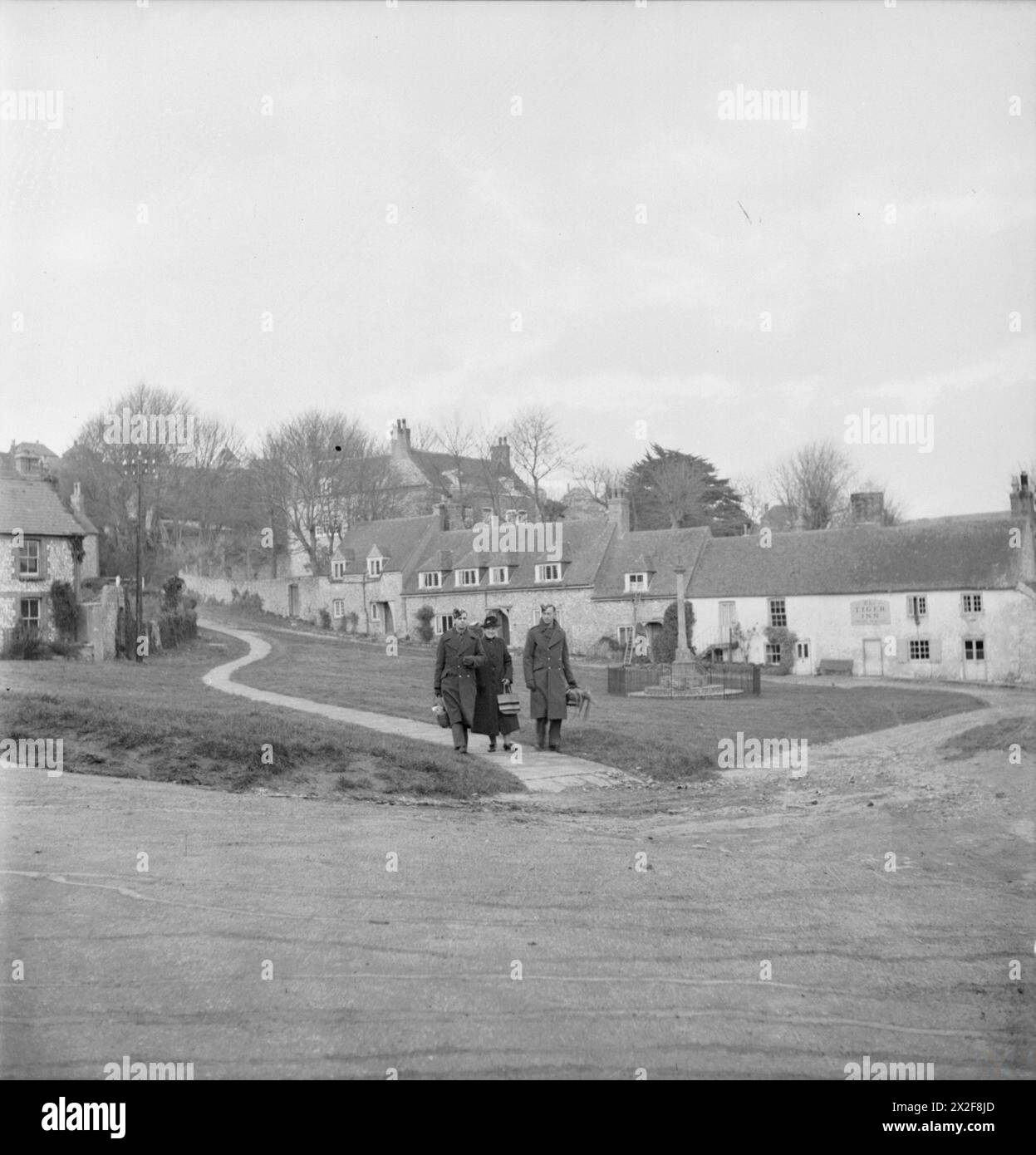 Mrs Bugler walks past the war memorial in East Dean, Sussex, in 1943 ...