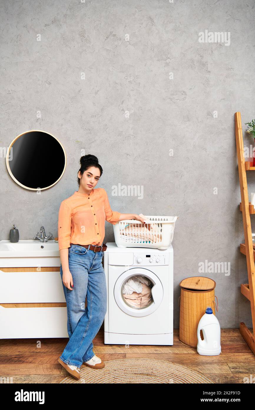 A casually dressed woman standing next to a washing machine, taking ...