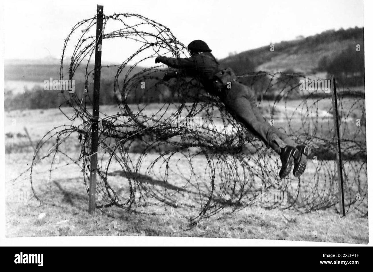 Commandos in training demonstrate crossing barbed wire obstructions ...