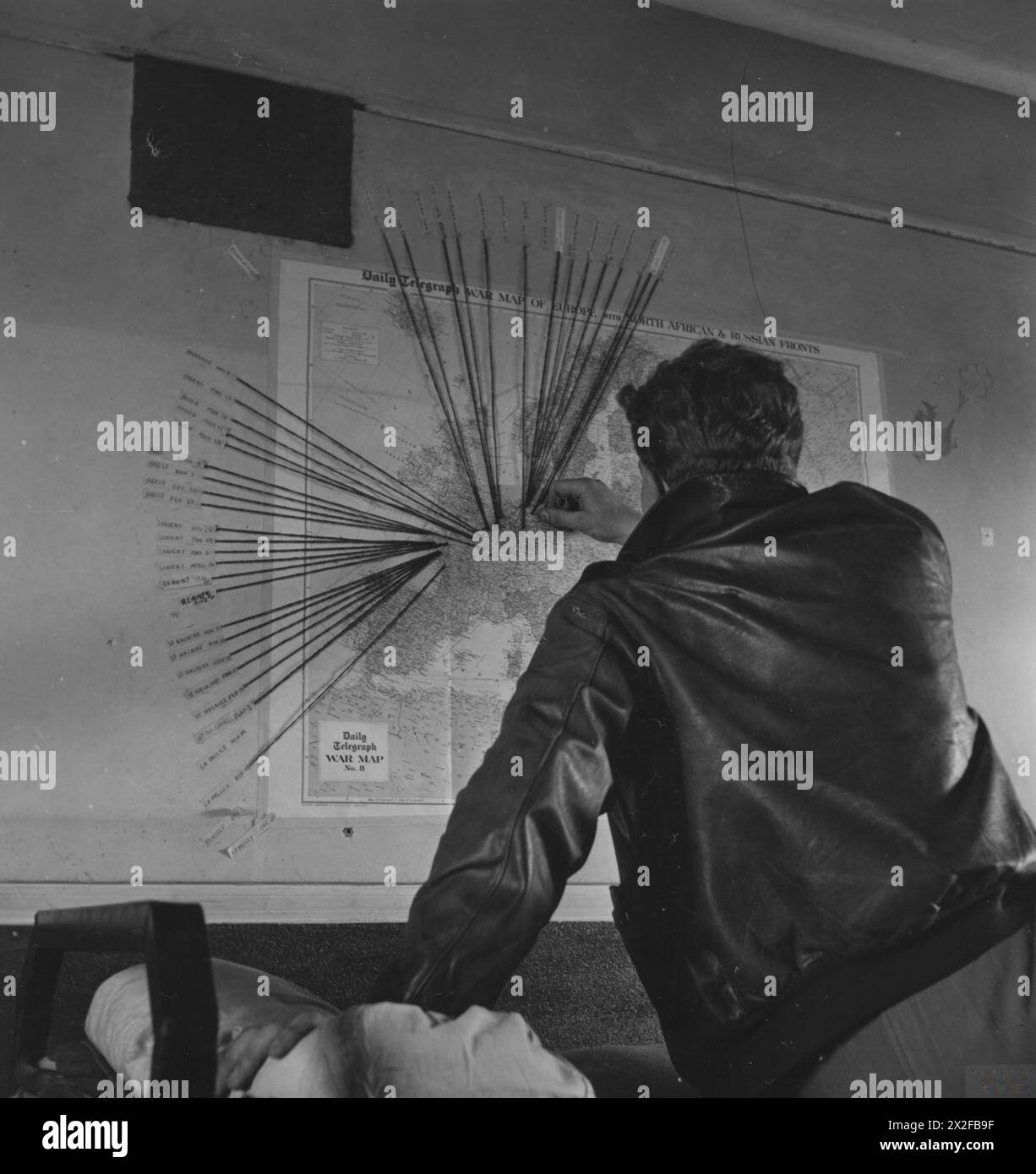 An airman of the 91st Bomb Group pins bombing targets onto a map inside ...