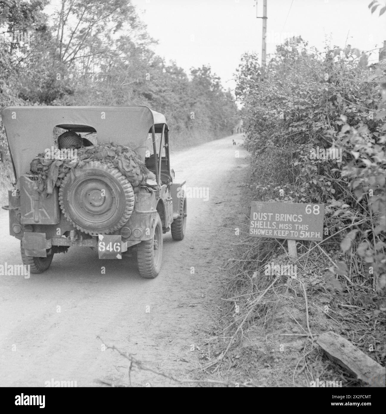 THE BRITISH ARMY IN NORMANDY 1944 - 'Dust brings shells'. A jeep passes ...