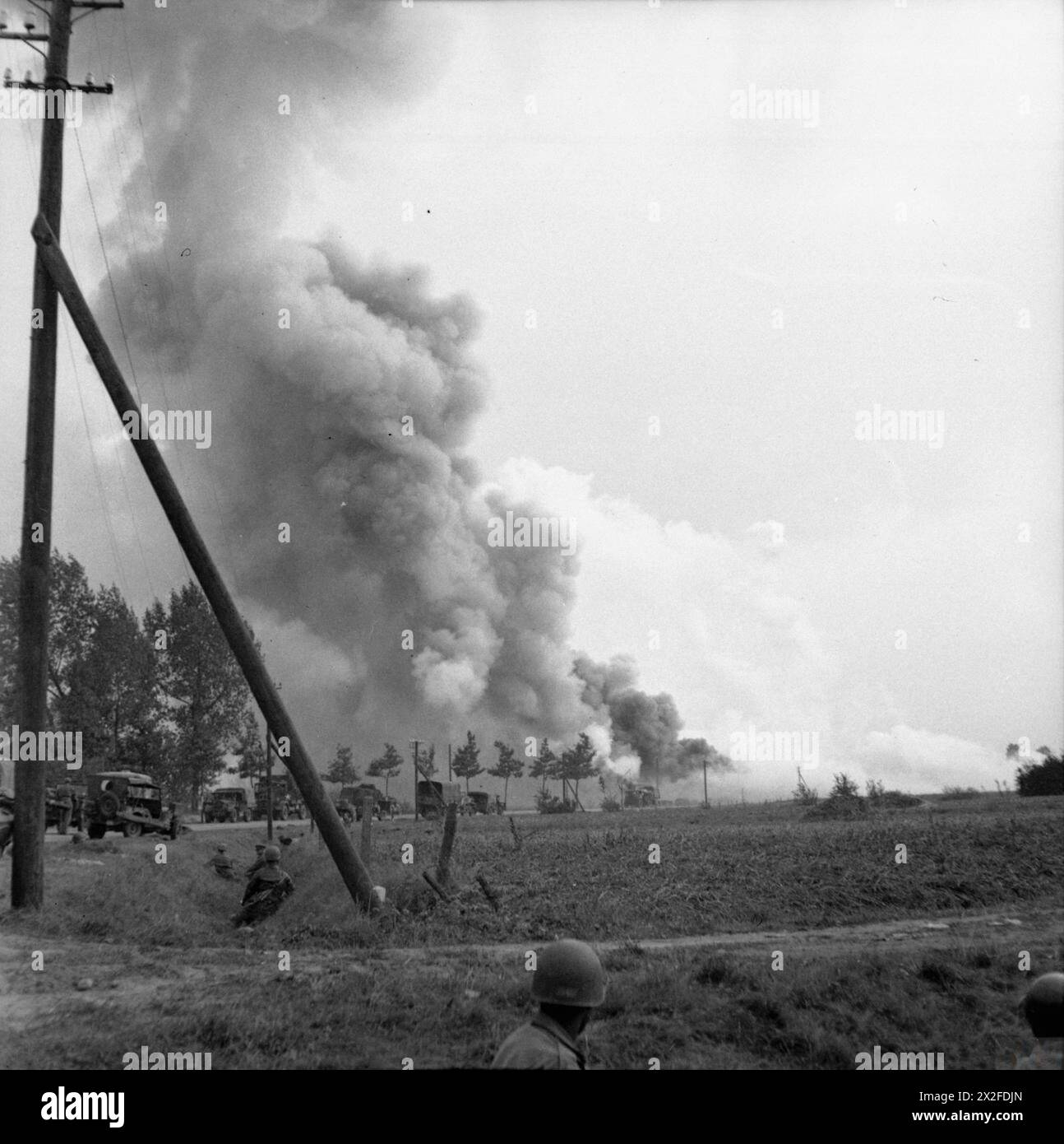 A British Army convoy of lorries moves under enemy artillery and mortar ...