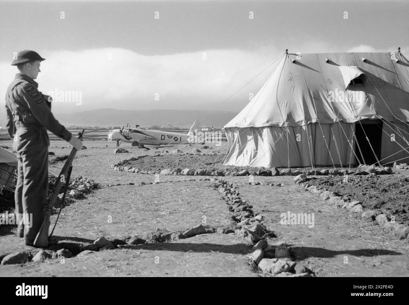 An airman stands guard at a tented RAF encampment at Lagens, Azores. A ...